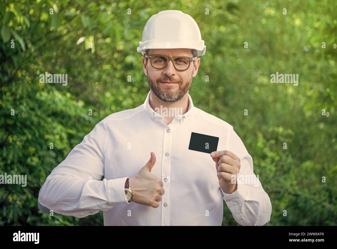 Man foreman in hardhat giving thumbs up showing blank contact card ...