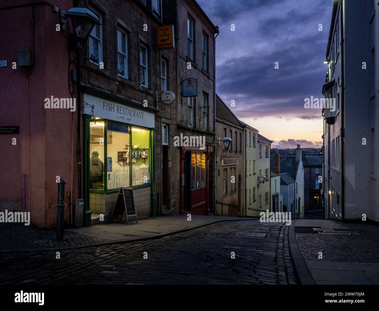 A lit shop window on damp cobbled street in Berwick on Tweed ...
