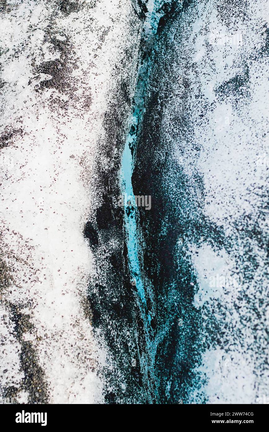 Blue ice crack between ice crack covered in black volcanic ash ice ...