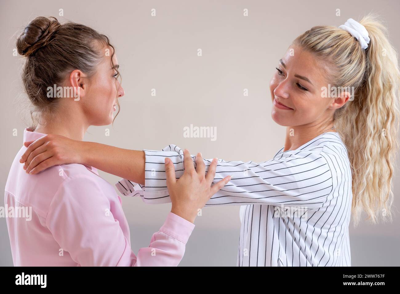 Complicity - young women face to face on a light gray background Stock ...