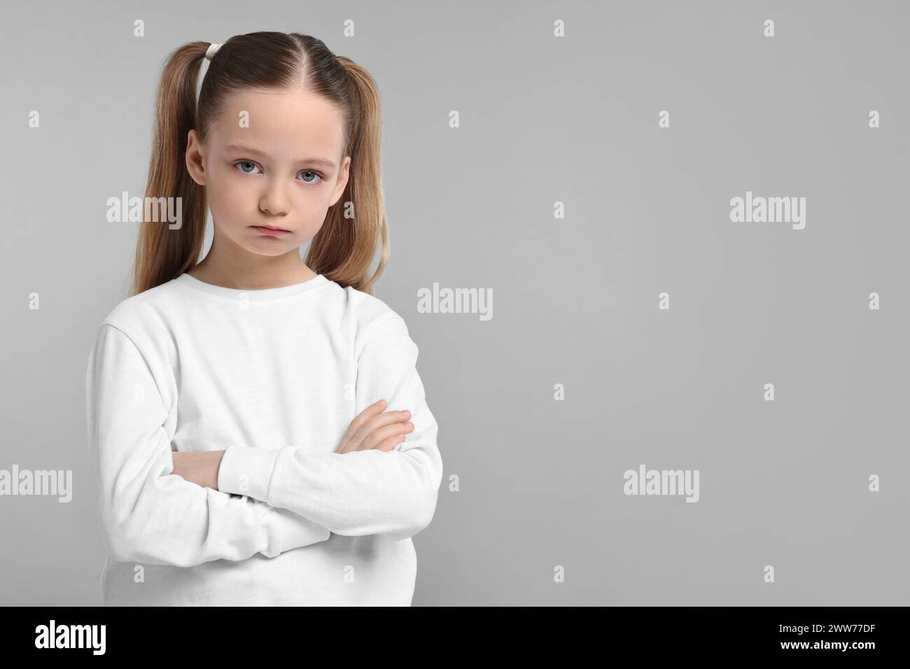 Portrait of sad girl with crossed arms on light grey background, space ...