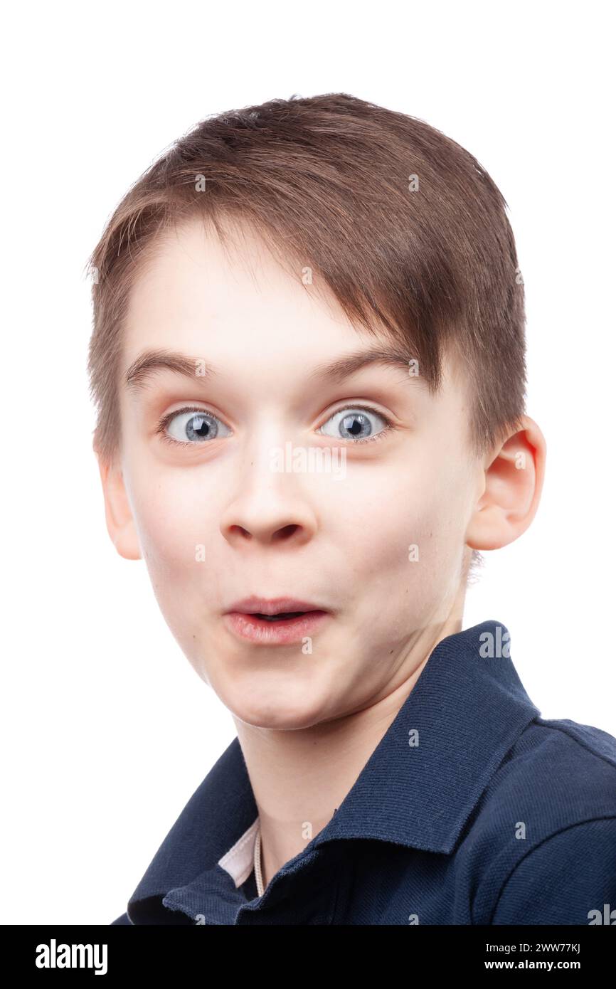 A young boy wearing blue polo shirt looks surprised with eyes wide open ...