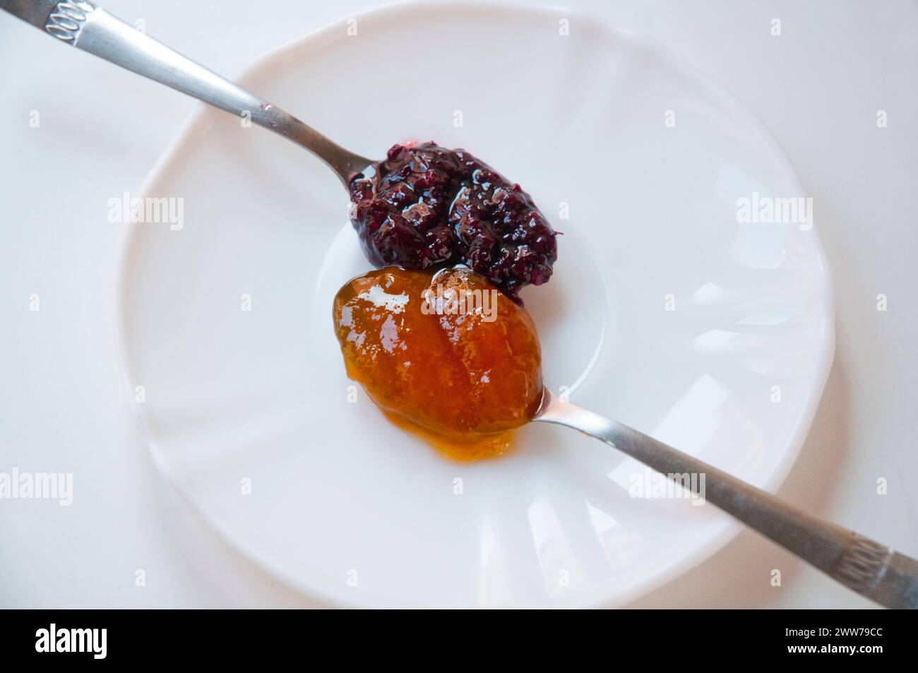 Two spoons with peach and strawberry jam on a dish Stock Photo - Alamy