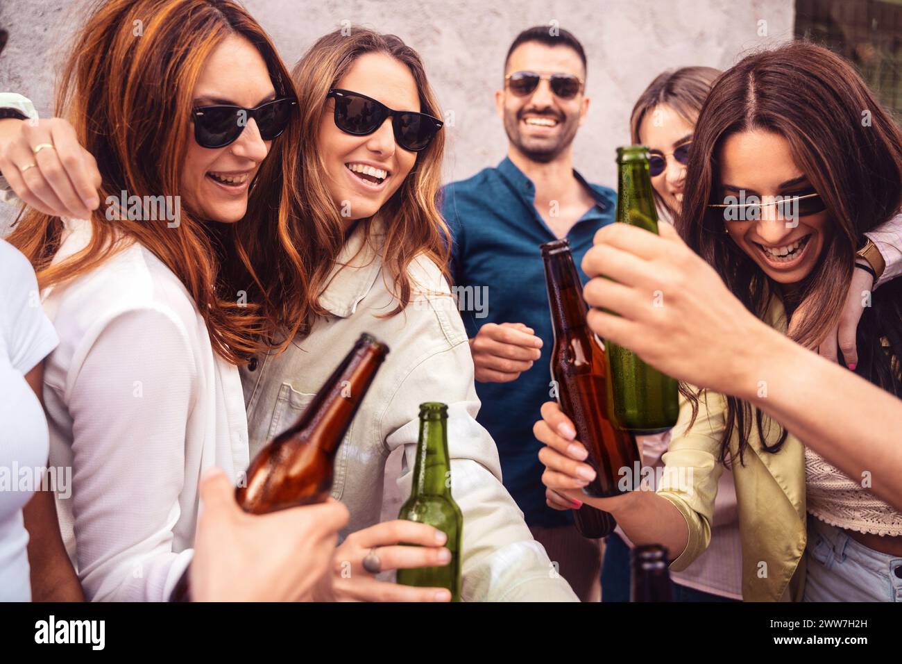 A vibrant group of friends - toasting with cold beers, sunglasses on ...