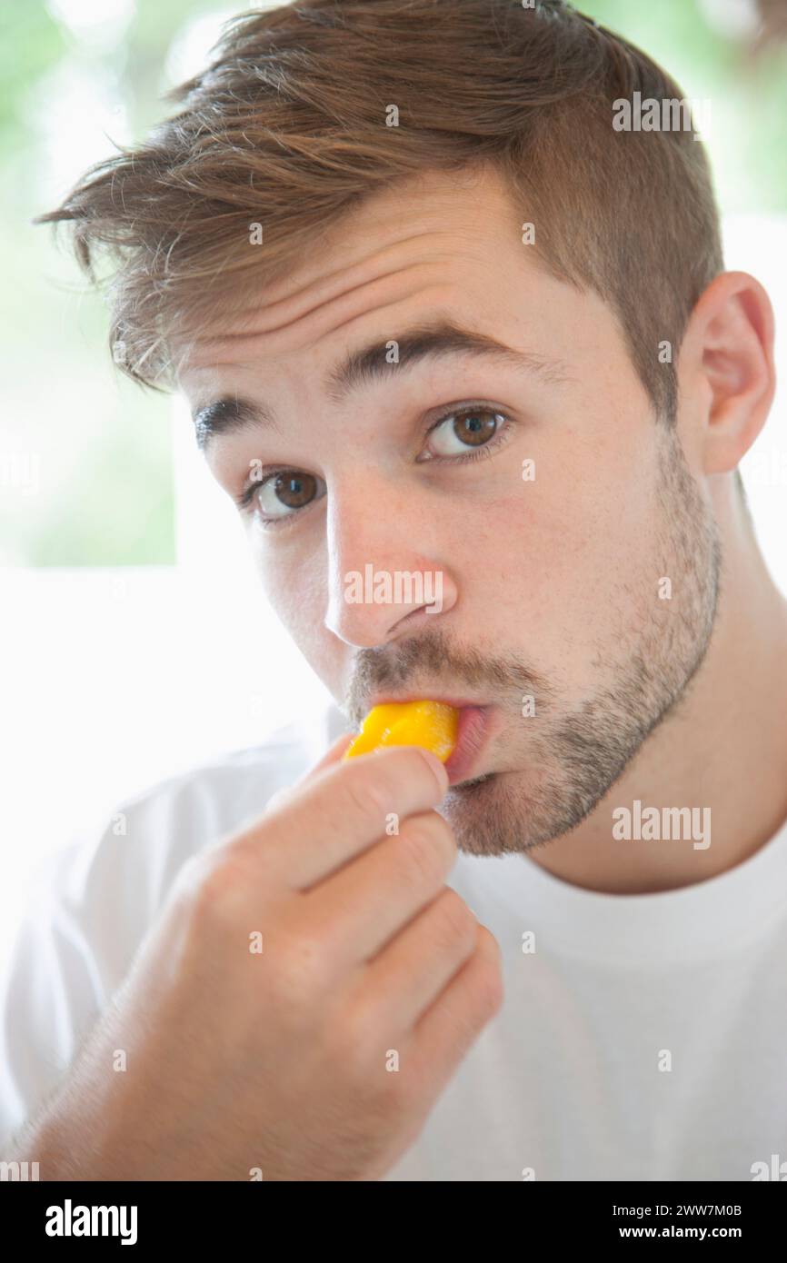 Man Biting Slice of Mango Stock Photo - Alamy