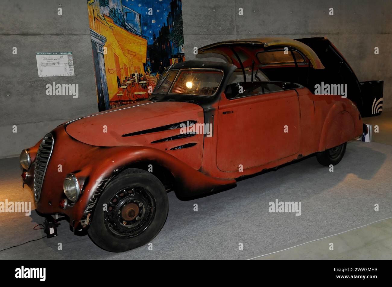 A red vintage car in unrestored condition with rust and patina ...
