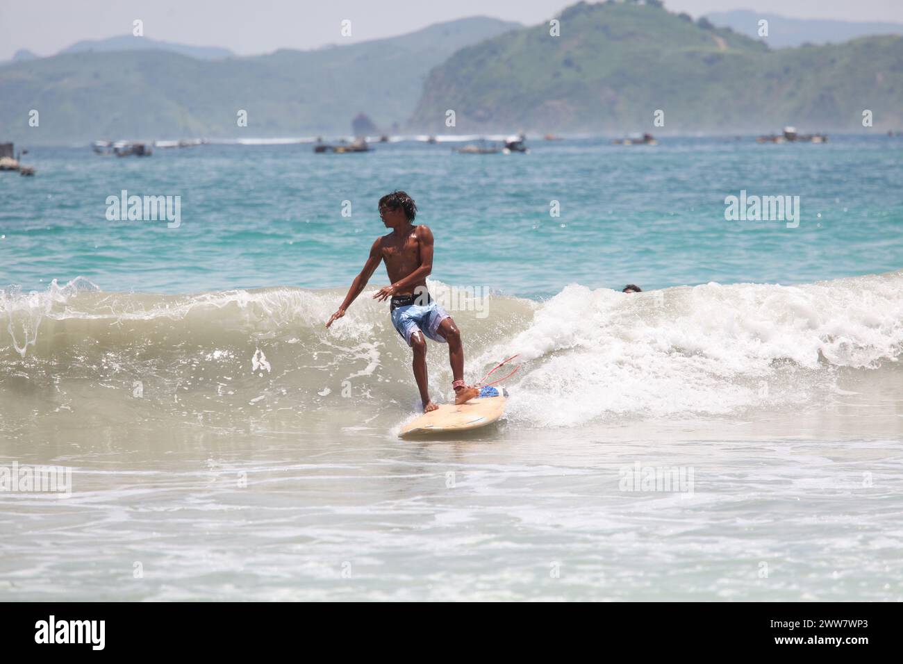 A surfer is enjoying the strong waves on the beach with his surfboard ...
