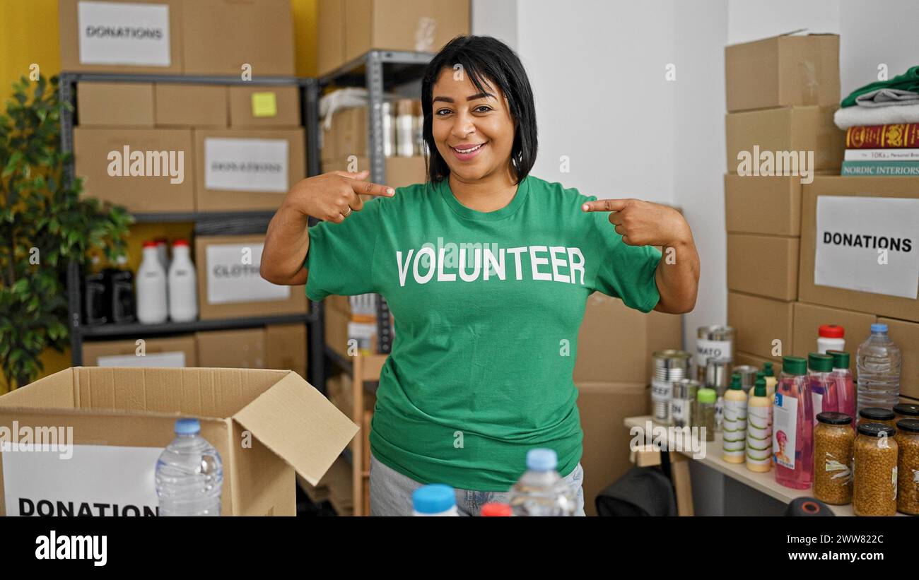 Hispanic woman volunteer pointing at herself in a warehouse full of ...