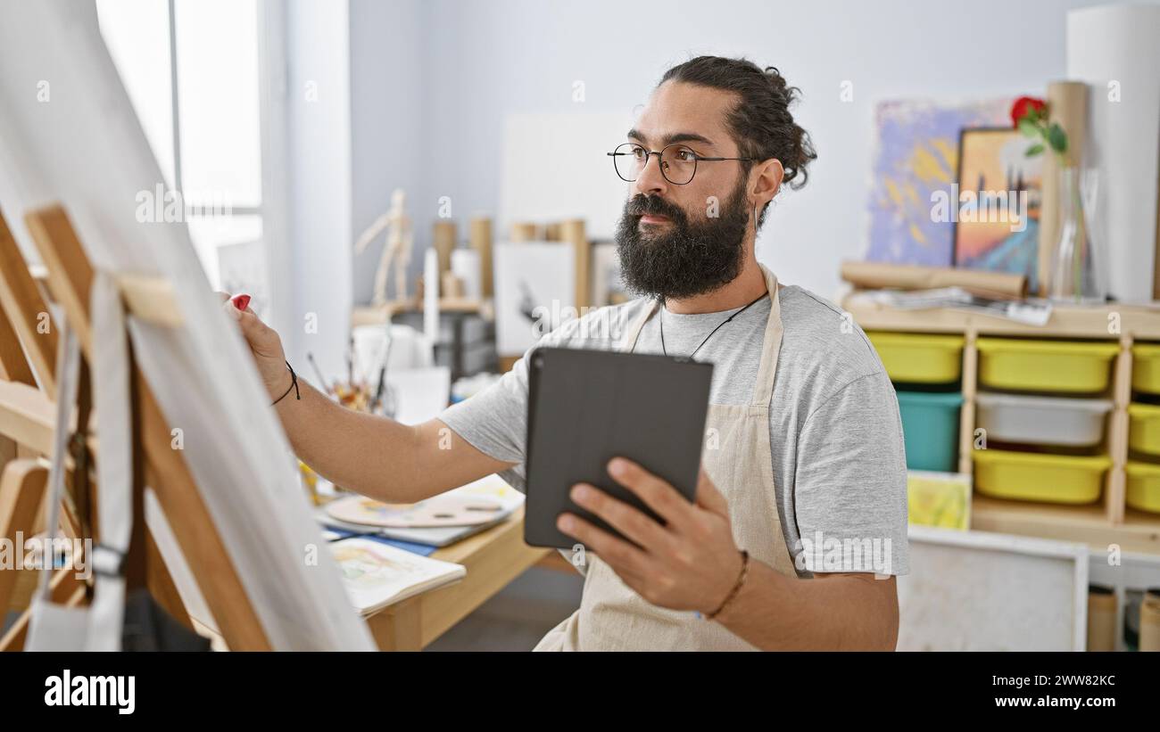 Hispanic male artist painting in a studio using digital tablet for ...