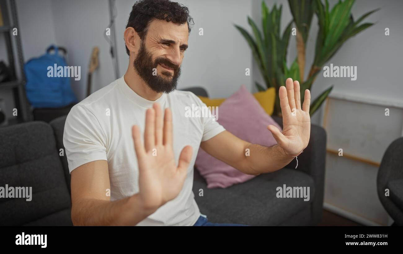 Bearded man gesturing stop with hands in a living room, reflecting ...