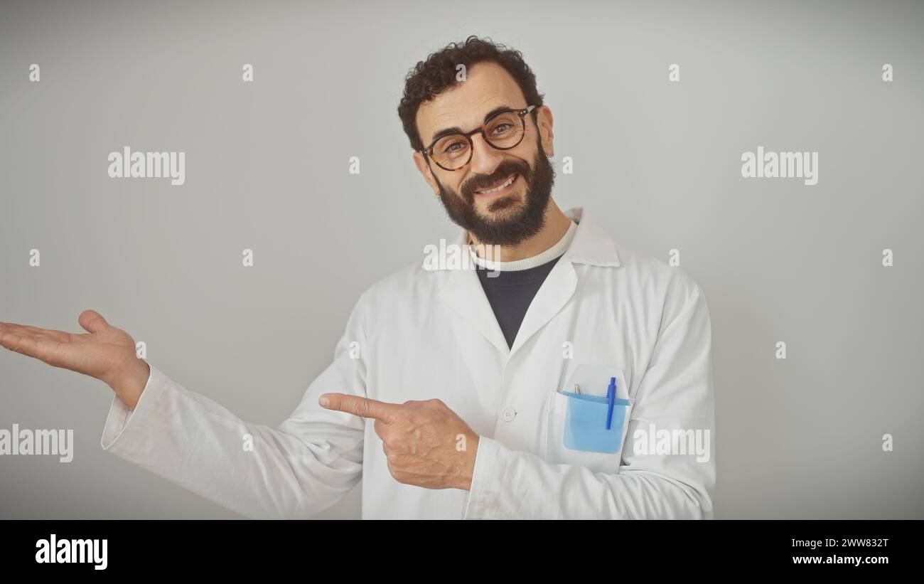 Smiling bearded man in white lab coat pointing aside, against a gray ...