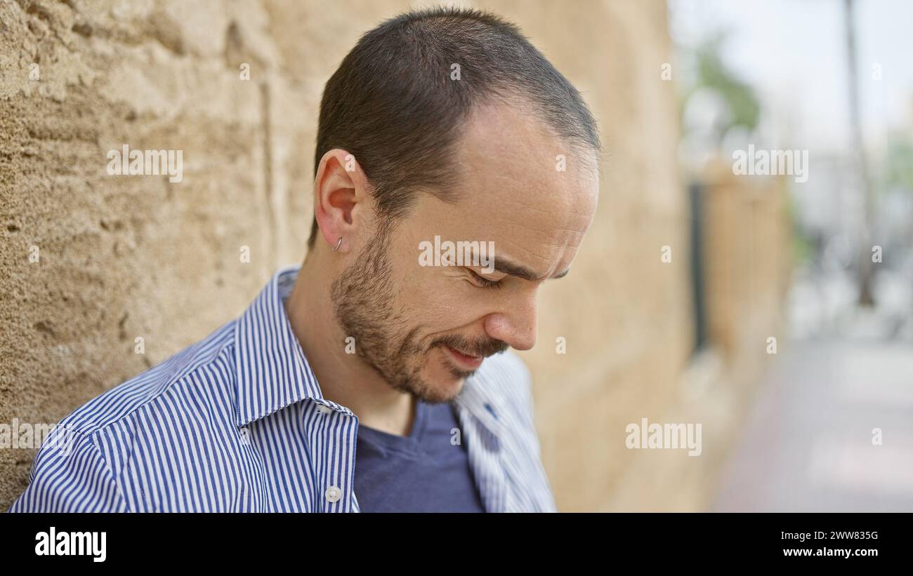 A smiling hispanic bald man with a beard, standing outdoors in a ...
