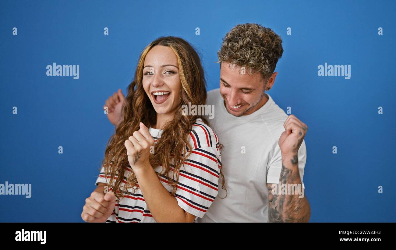 A joyful couple dances against a vibrant blue background, showcasing ...