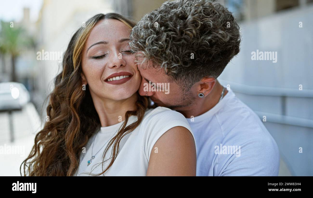 A loving couple embraces on a city street, with the man kissing the ...