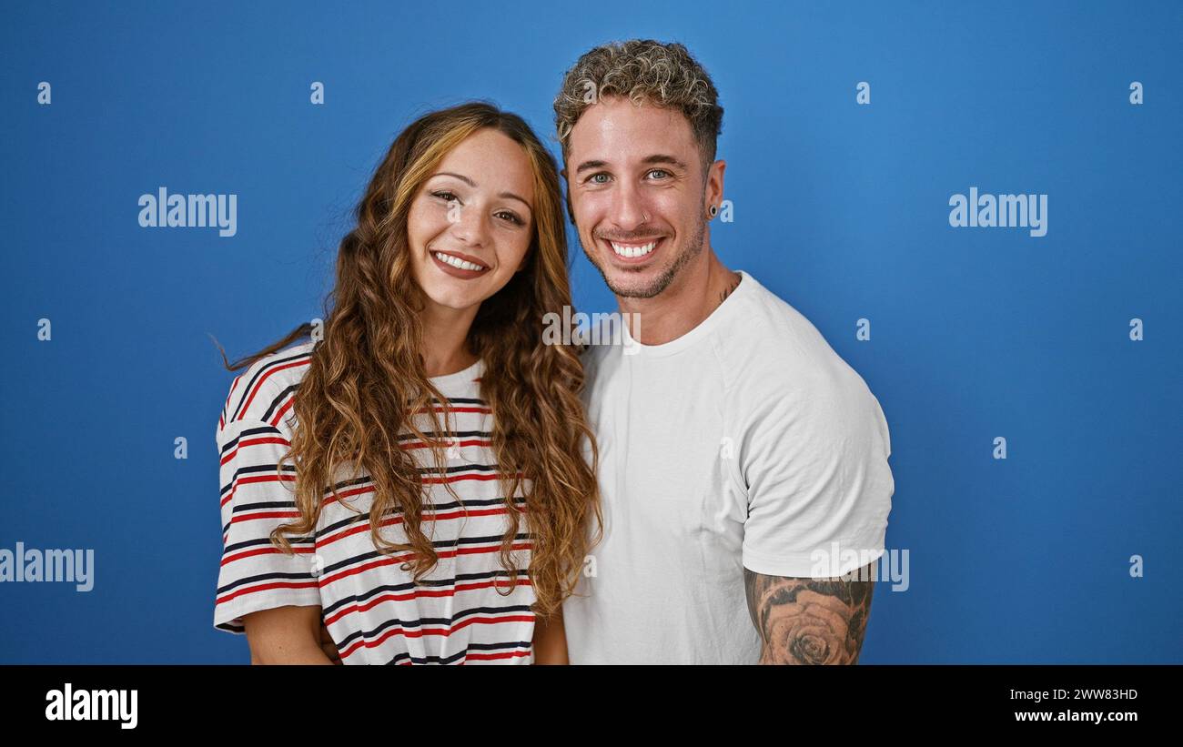 A happy couple embracing against a solid blue background, conveying ...