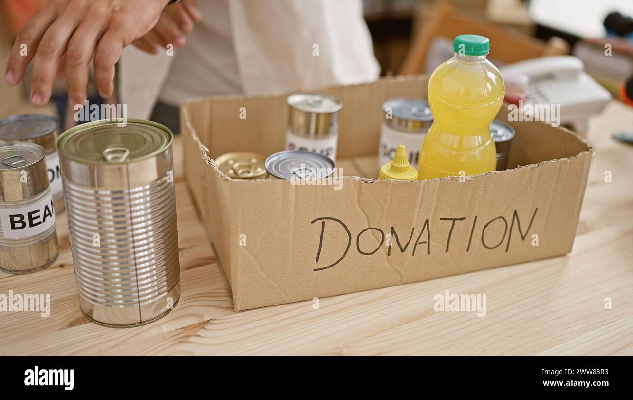 Close-up of a cardboard donation box with cans and a juice bottle on a ...
