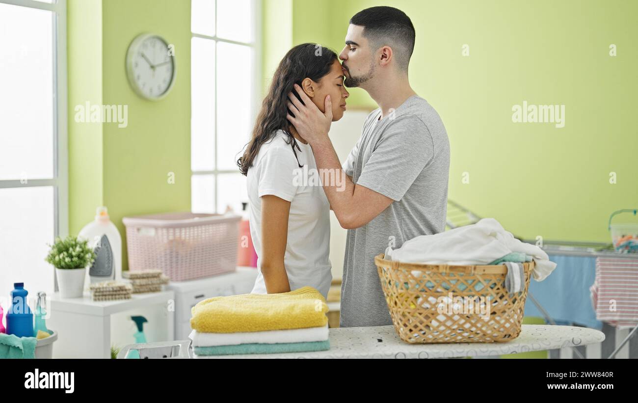 Beautiful couple together in love sharing chores in the laundry room ...