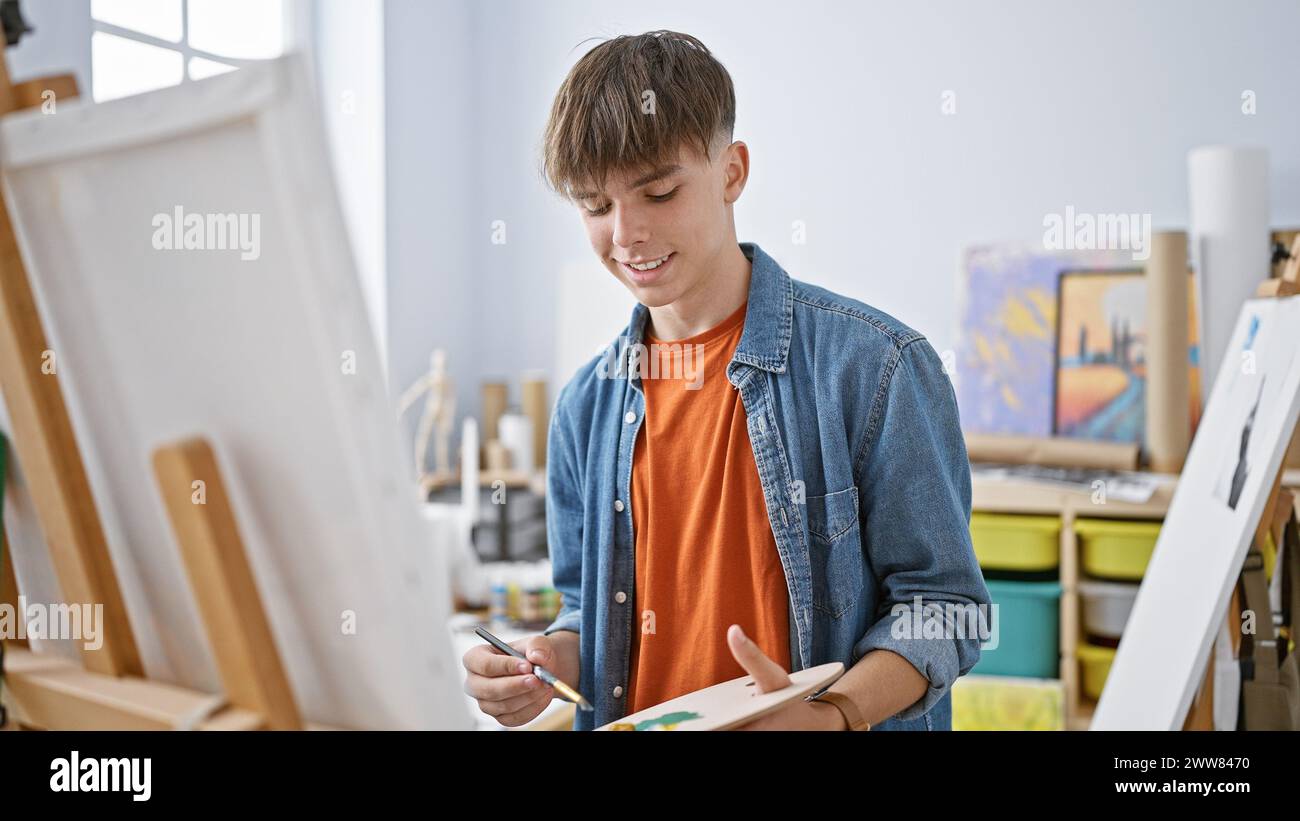 Caucasian teenage boy painting on canvas in art studio class, focused ...