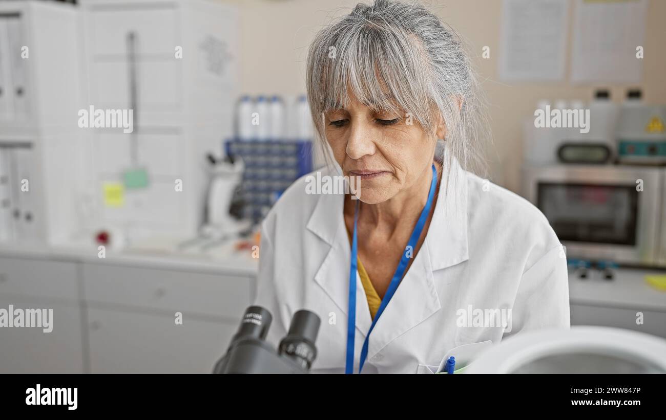 A middle-aged woman with grey hair working focused in a laboratory ...
