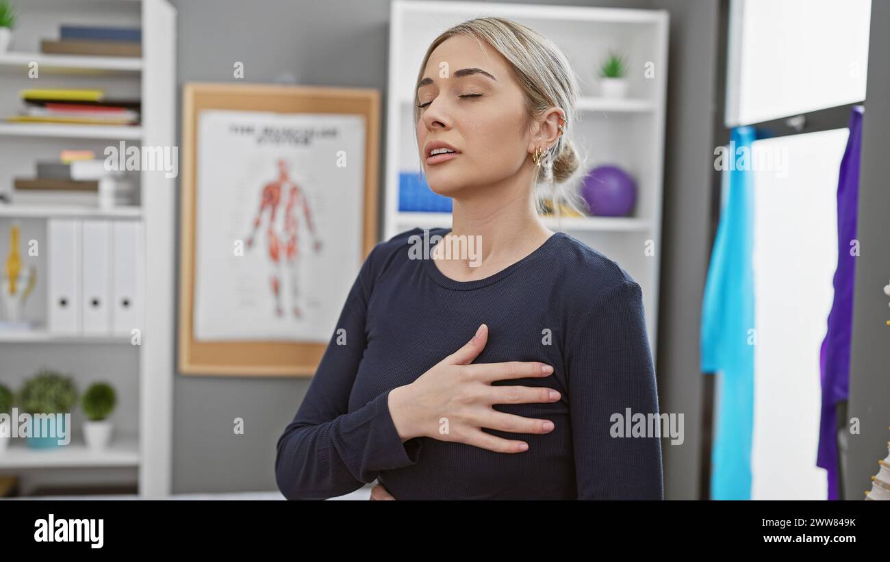 Blonde woman in pain holding chest in a medical office with anatomy ...