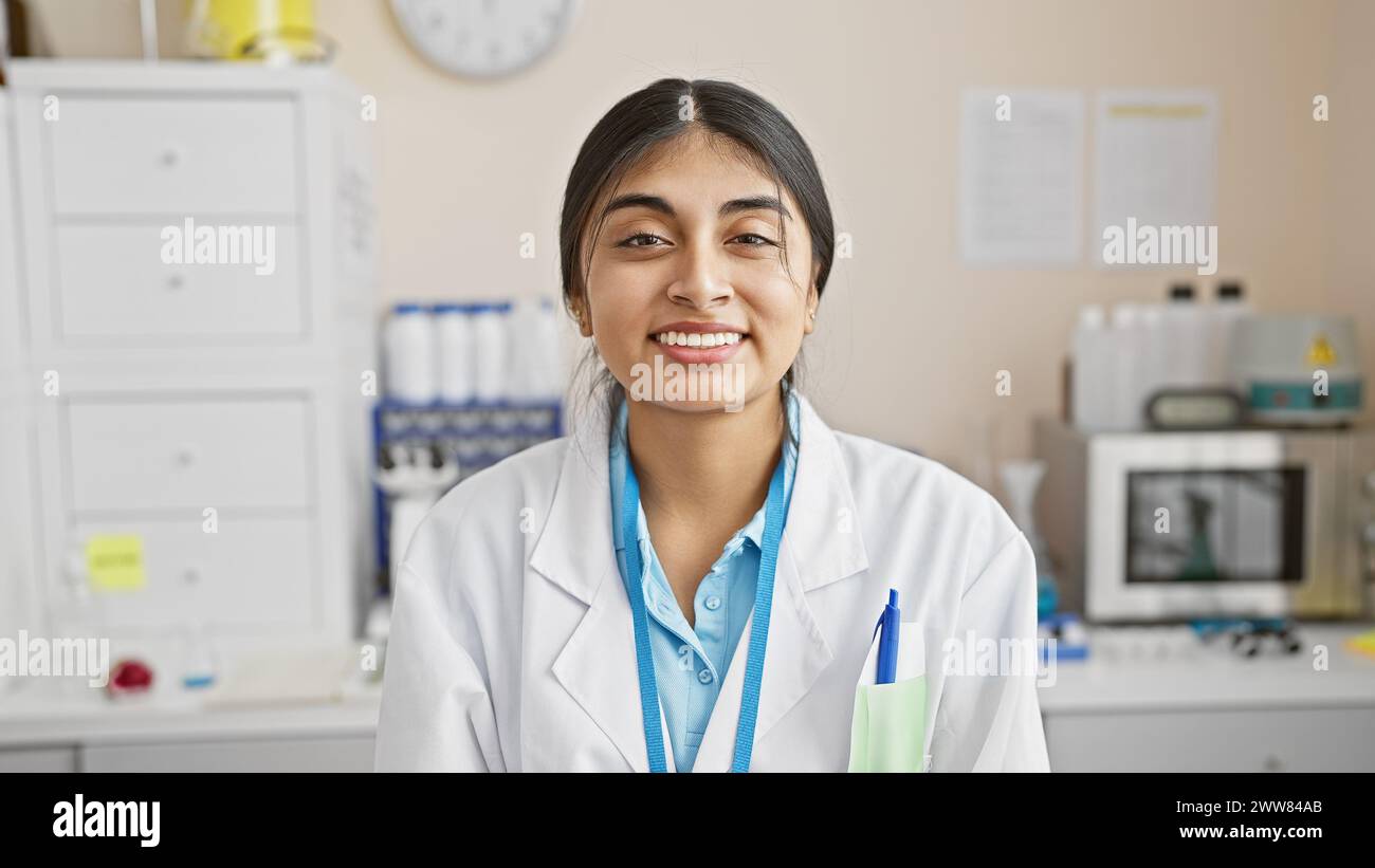 Young indian woman with long hair, smiling in a white lab coat in a ...