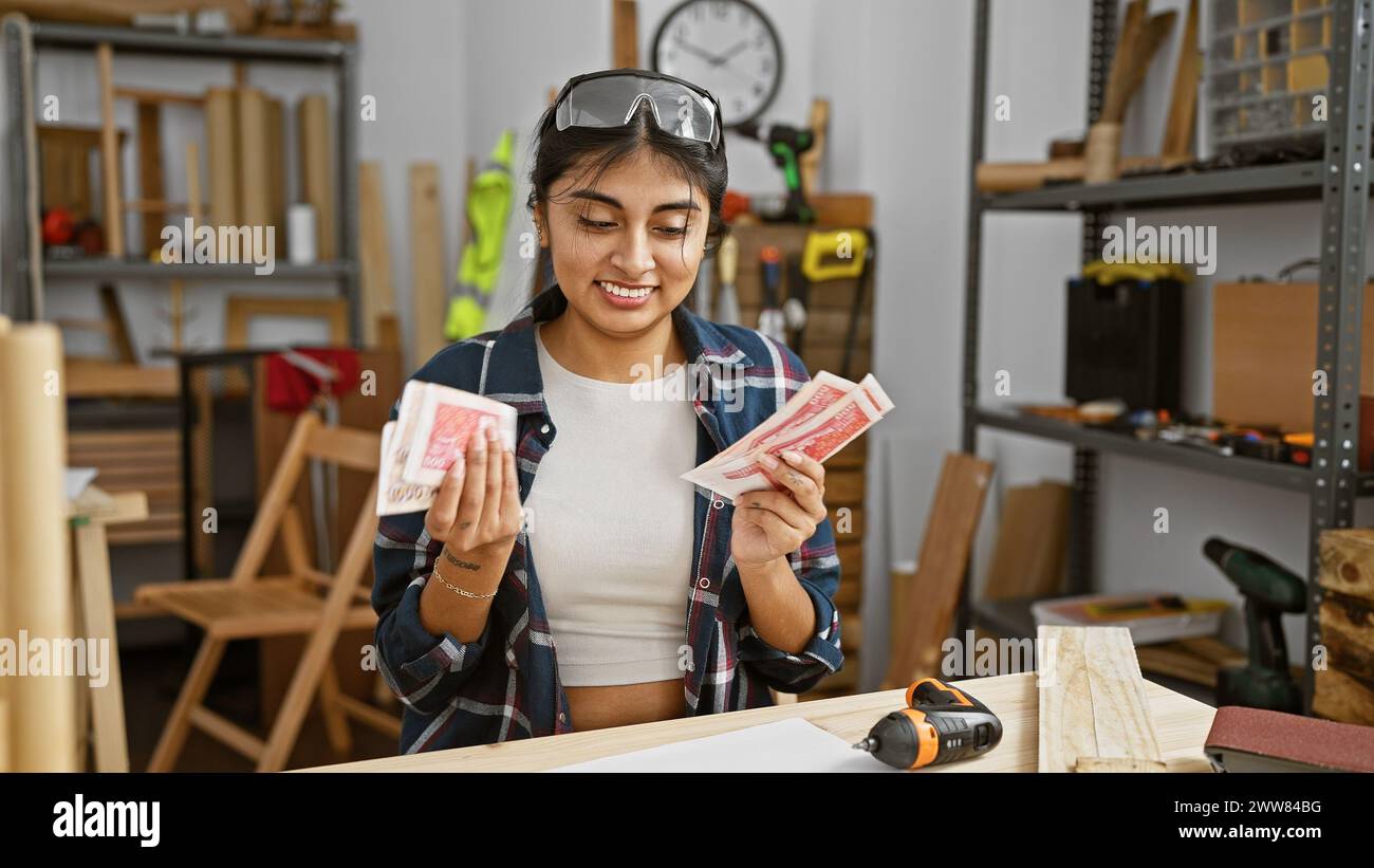 A young indian woman smiles while holding icelandic krona in a well ...
