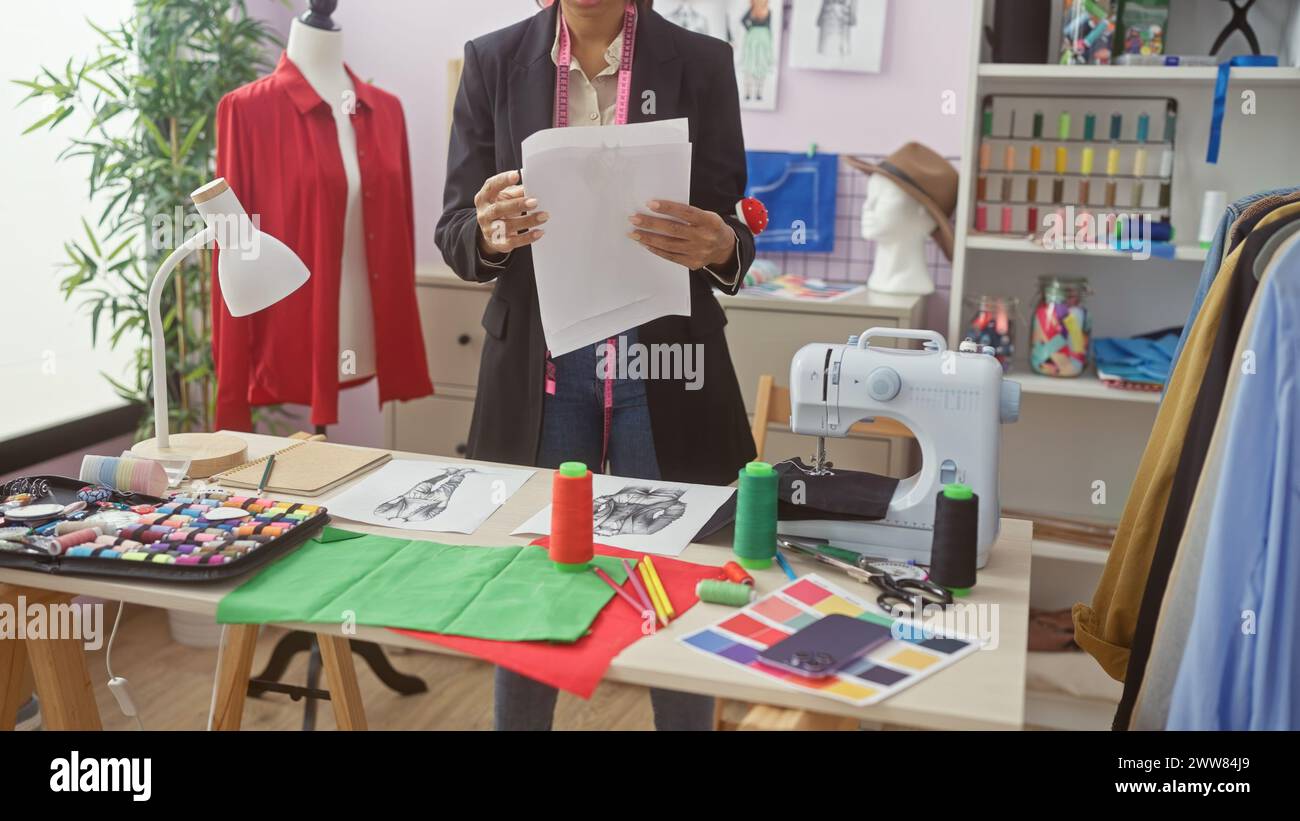 African woman tailor examining patterns in a colorful atelier with ...