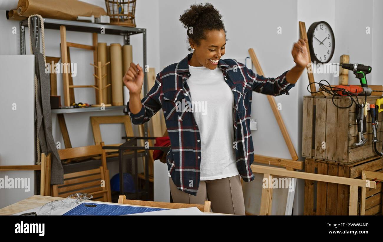 A cheerful young woman having fun in a carpentry workshop lined with ...