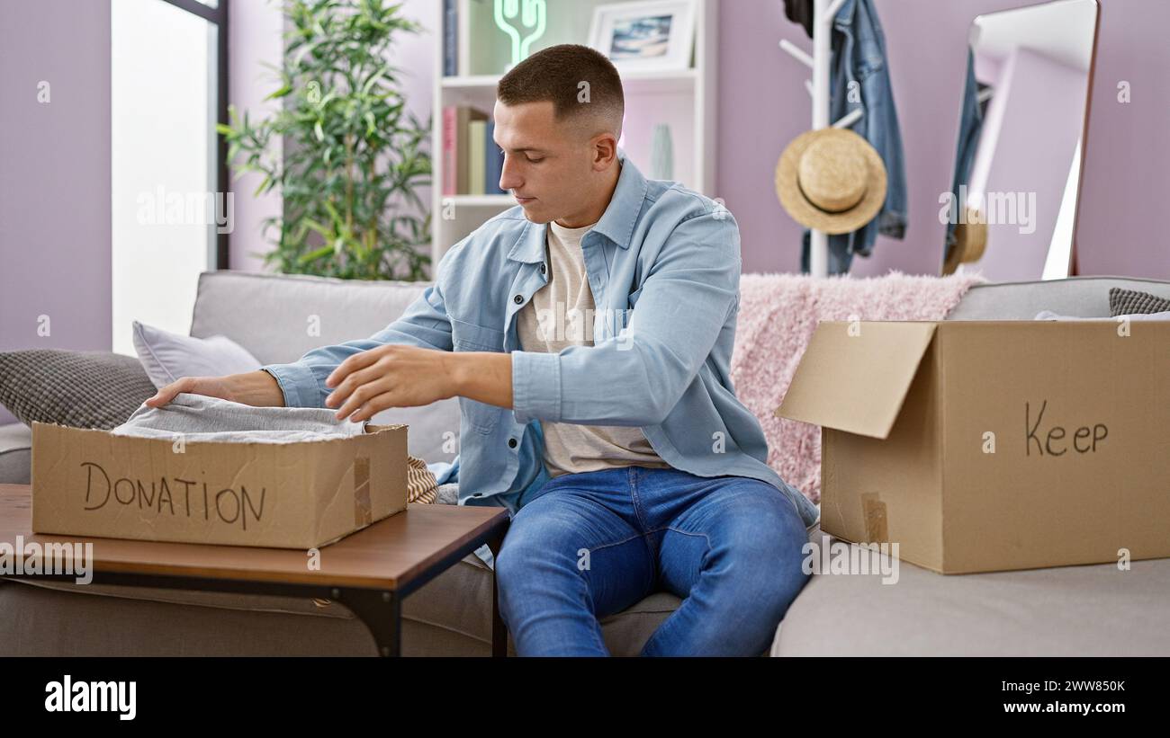 A young man sorts clothing into donation boxes in a living room ...