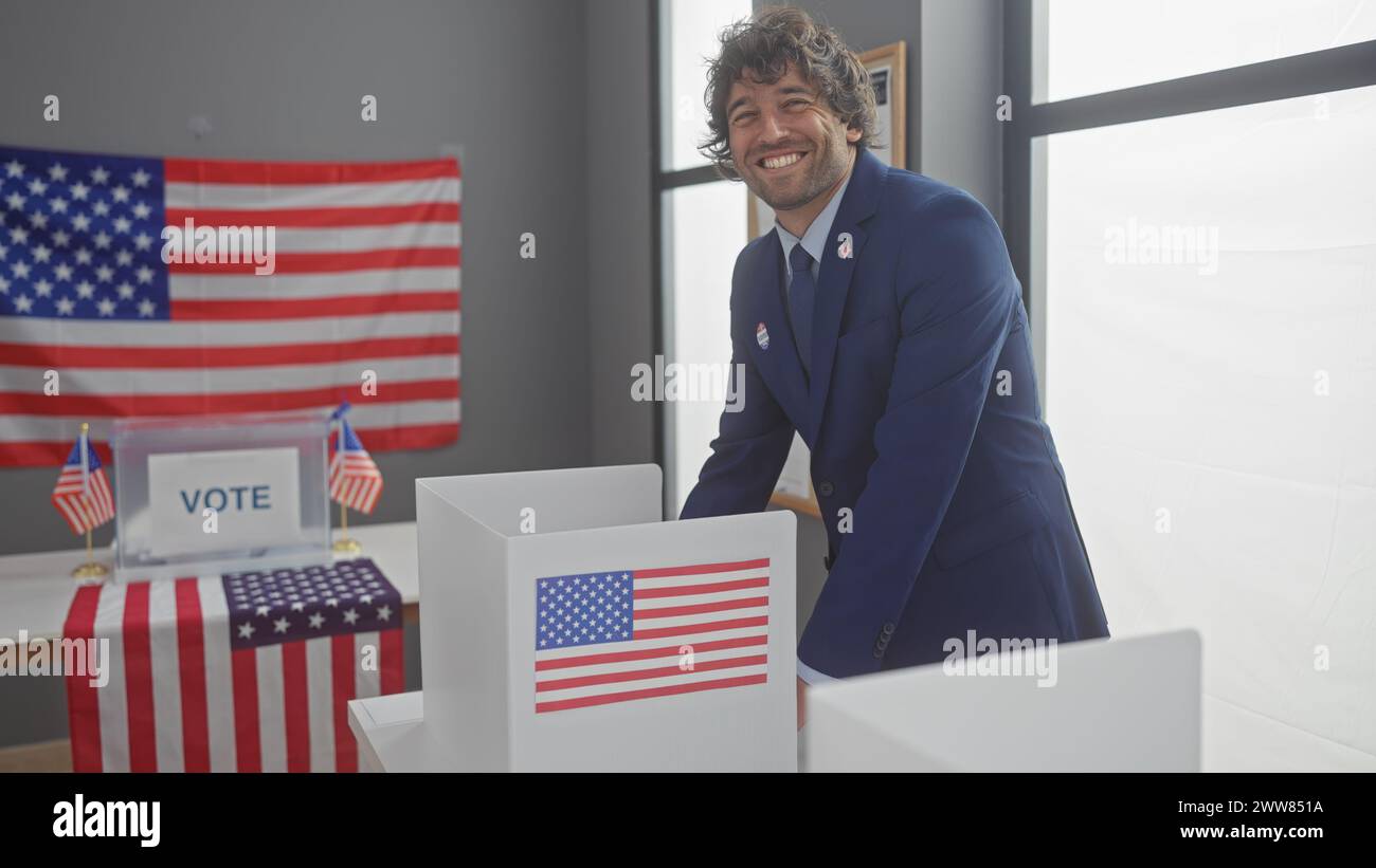 A smiling young hispanic man with a beard dressed in a suit stands by a ...