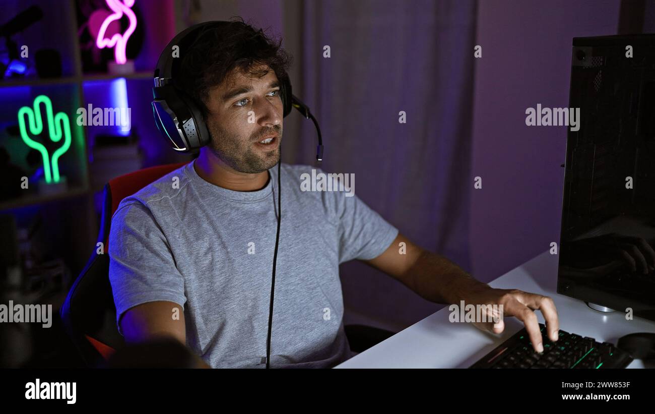 Focused man with beard gaming at night in a dark room illuminated by ...