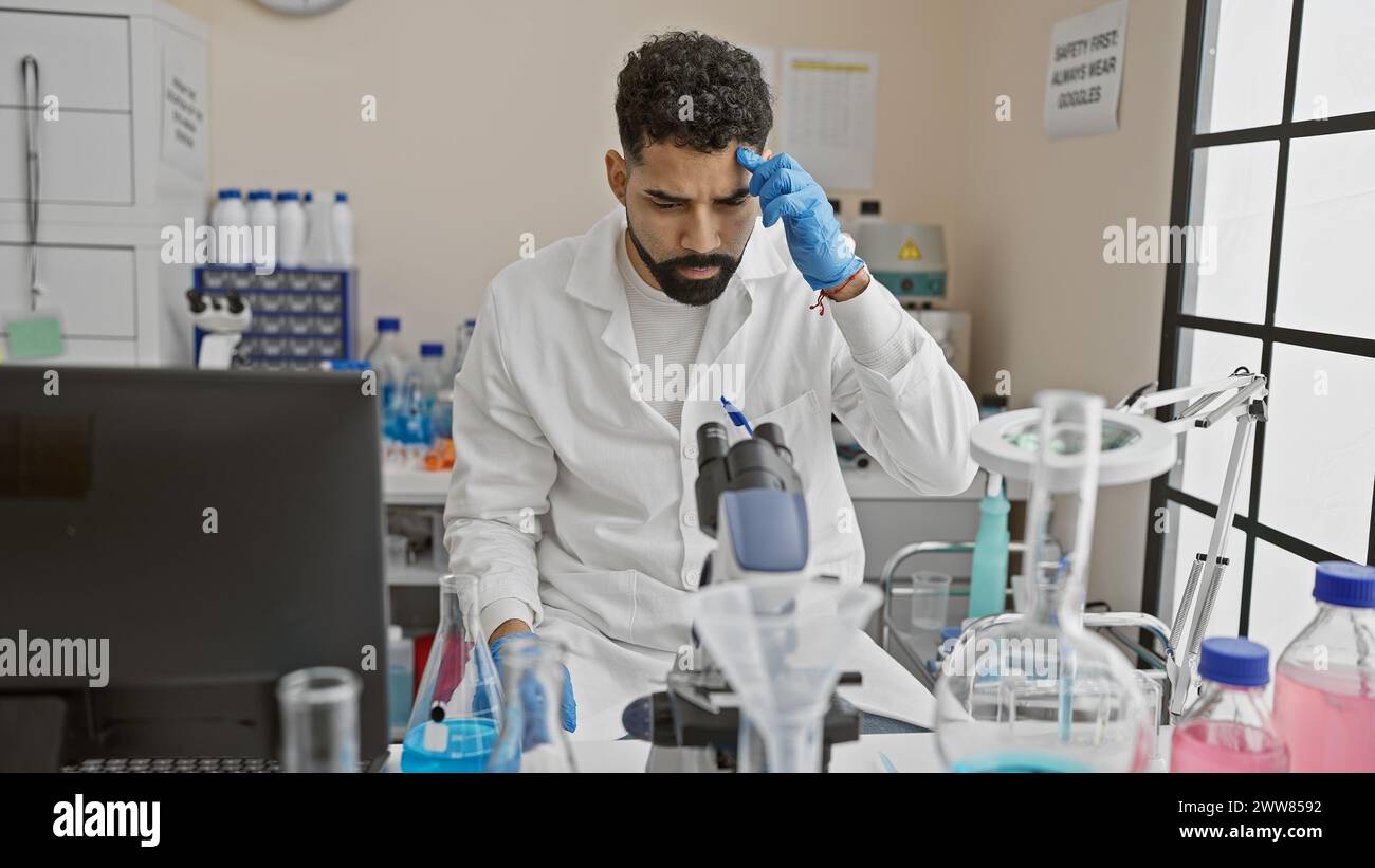 A young man in lab coat exhibits concentration while working amidst ...