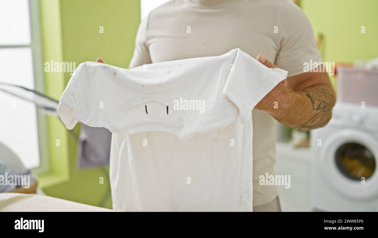 Young bearded man folding laundry in a bright utility room Stock Photo ...