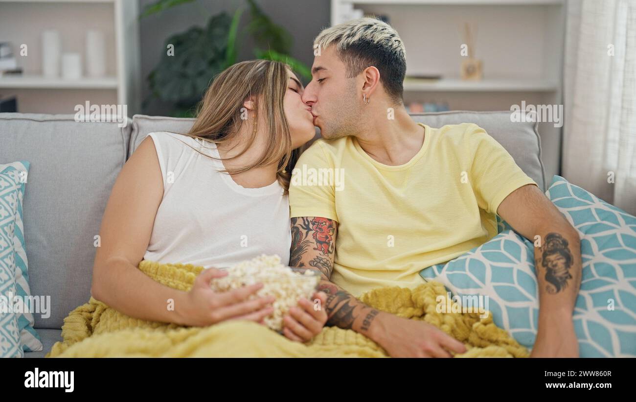 Beautiful couple eating popcorn kissing at home Stock Photo - Alamy