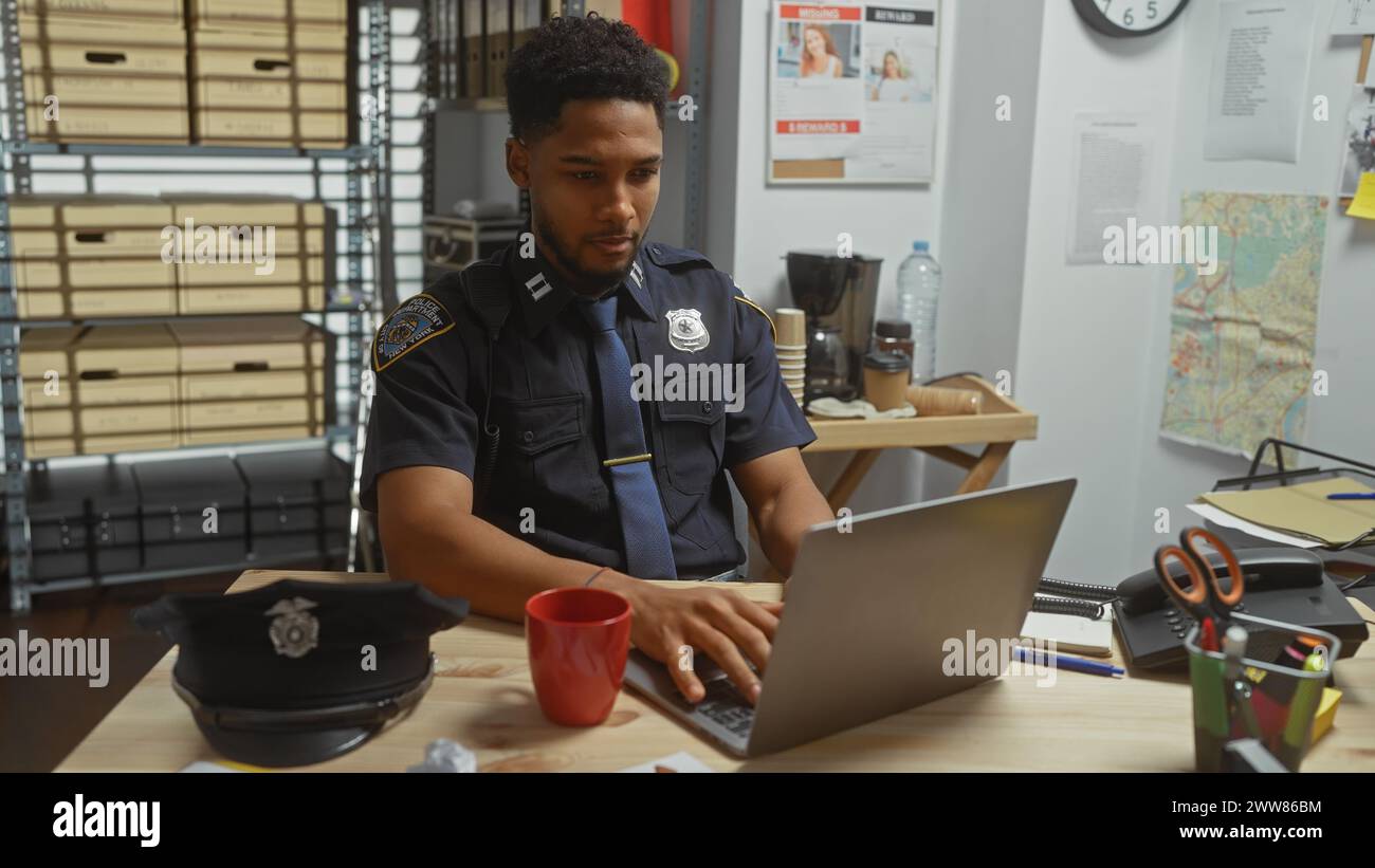 An african american male police officer analyzes evidence on a laptop ...