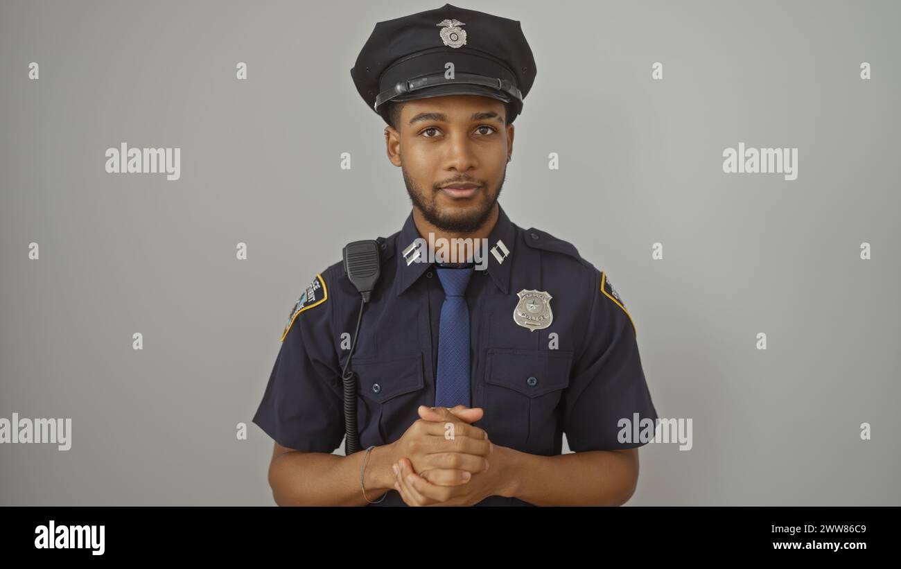 Handsome african american police officer with clasped hands against a ...