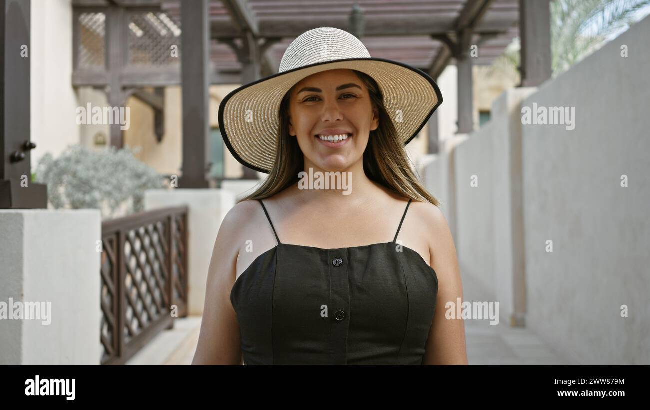 A smiling young adult hispanic woman wearing a sunhat in the ...