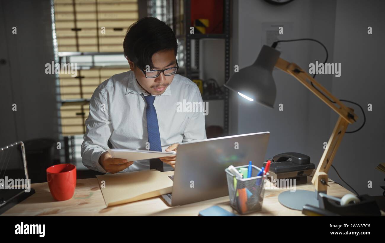 Focused asian man investigating crime evidence in a dimly lit detective ...