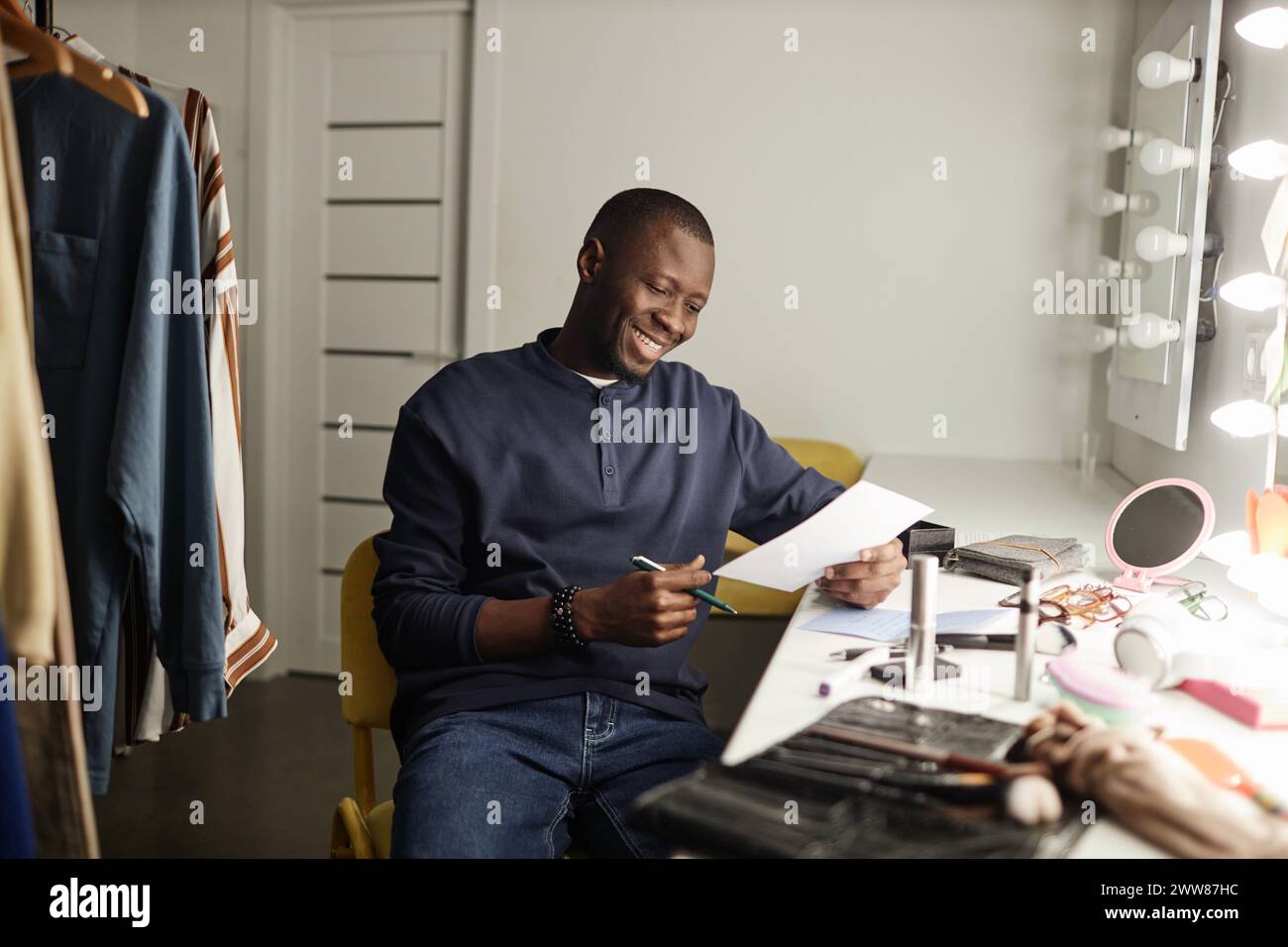 Portrait of smiling Black man reading script while preparing for ...