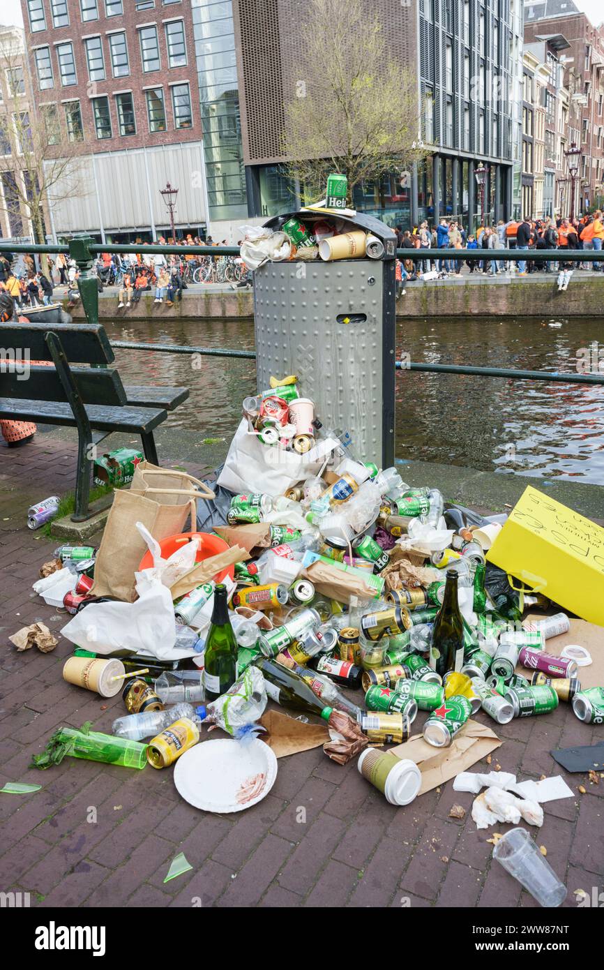 A trash bin spills over with cans and food waste, showing a messy ...