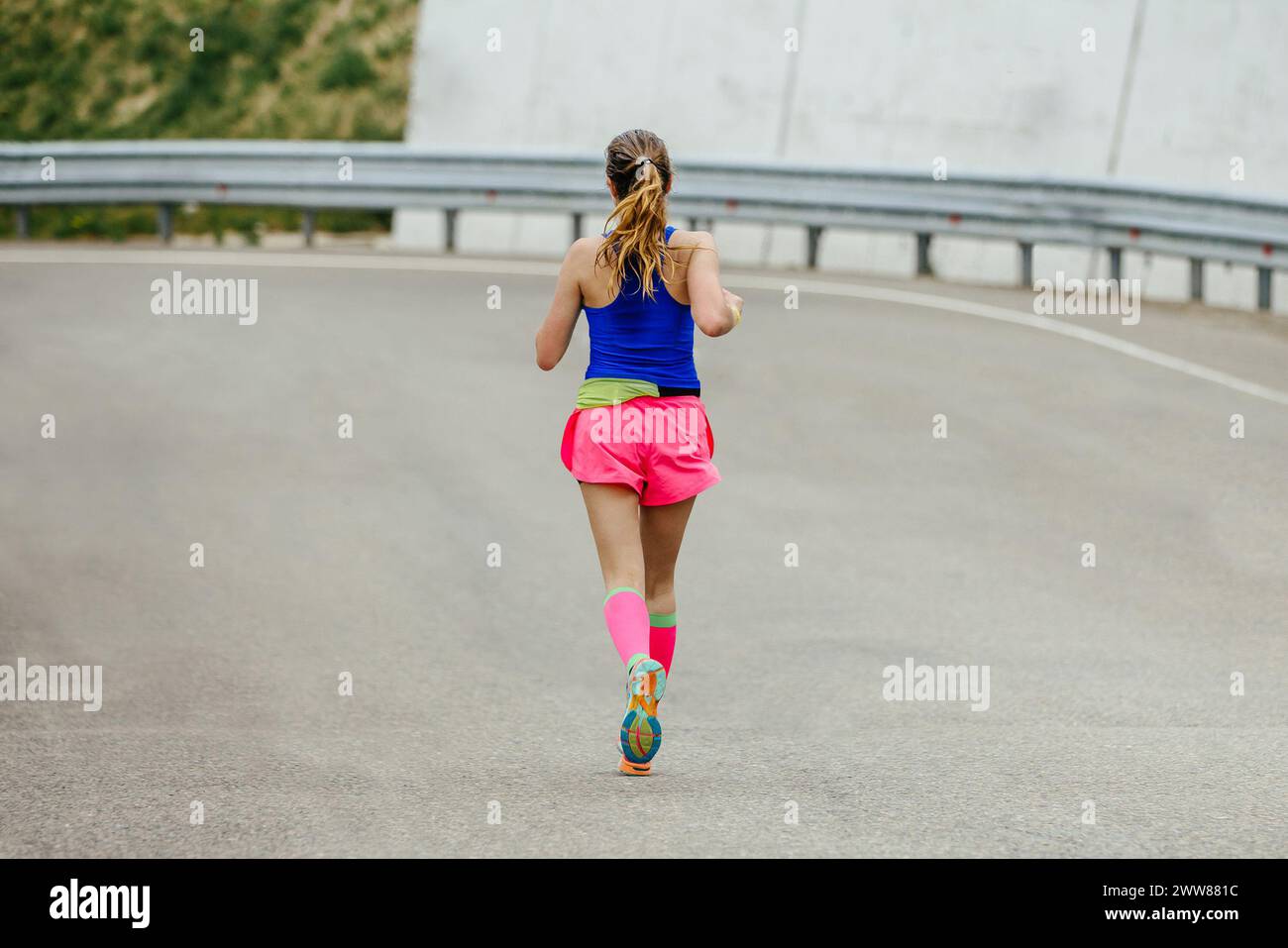 rear view woman running down road in bright sportswear Stock Photo - Alamy