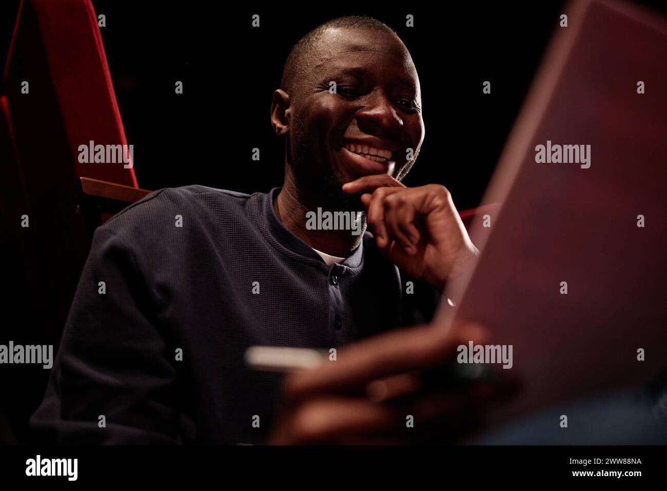 Low angle portrait of smiling African American artist reading lines and ...