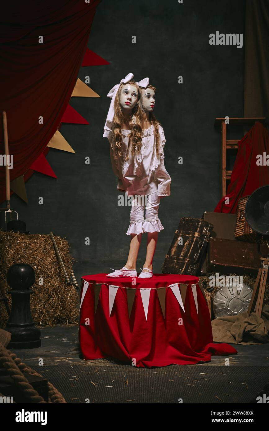 Siamese twin girls in white vintage costumes with makeup standing on ...