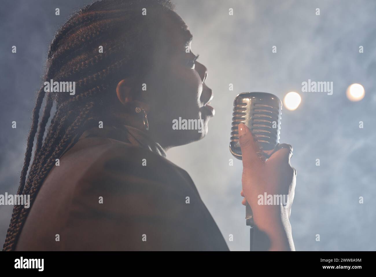 Side view portrait of African American woman singing to microphone on ...