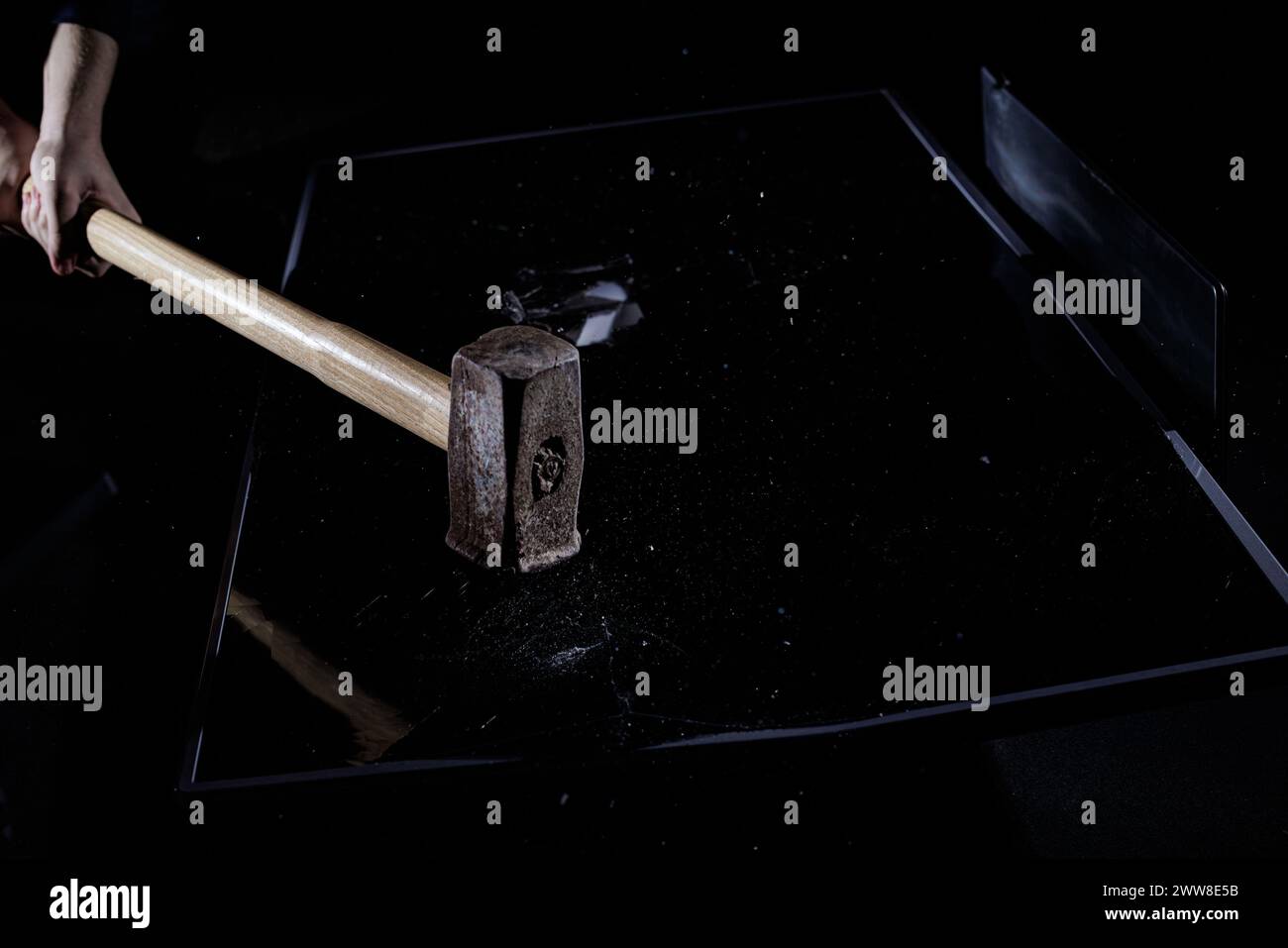Man holding a sledgehammer, hitting and smashing a plasma television ...