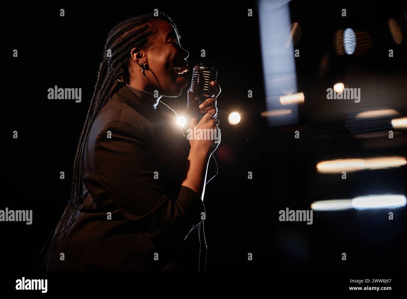 Side view portrait of African American woman singing to microphone ...