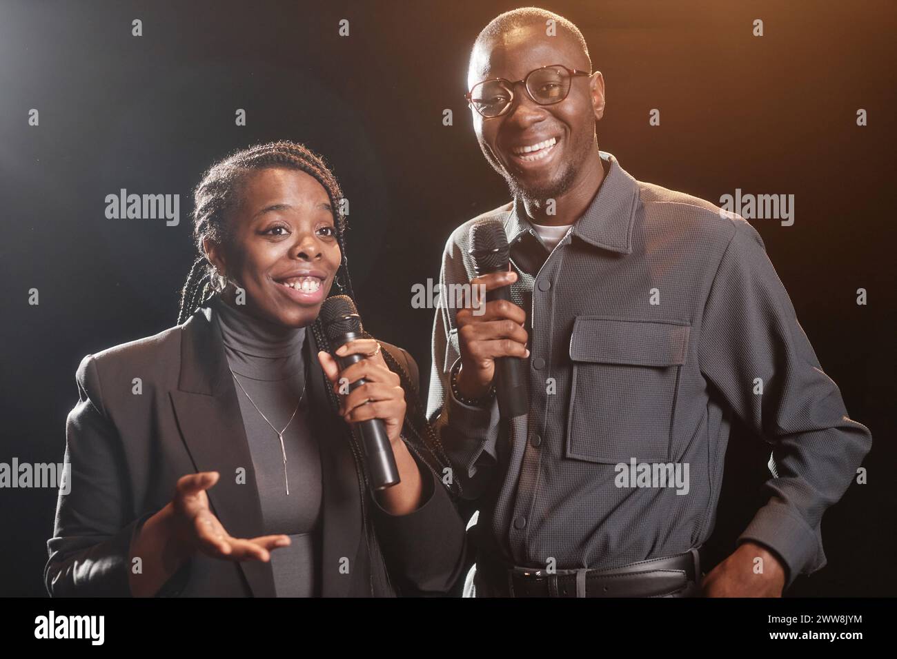 Waist up of African American couple on stage speaking to microphone ...
