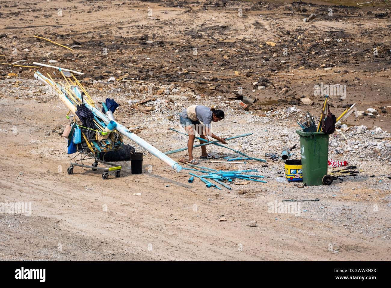 A female waste picker is seen collecting blue plastic pipes for water ...