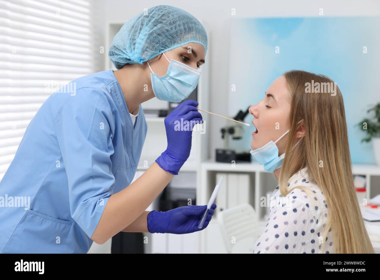 Laboratory testing. Doctor taking sample from patient's mouth with ...