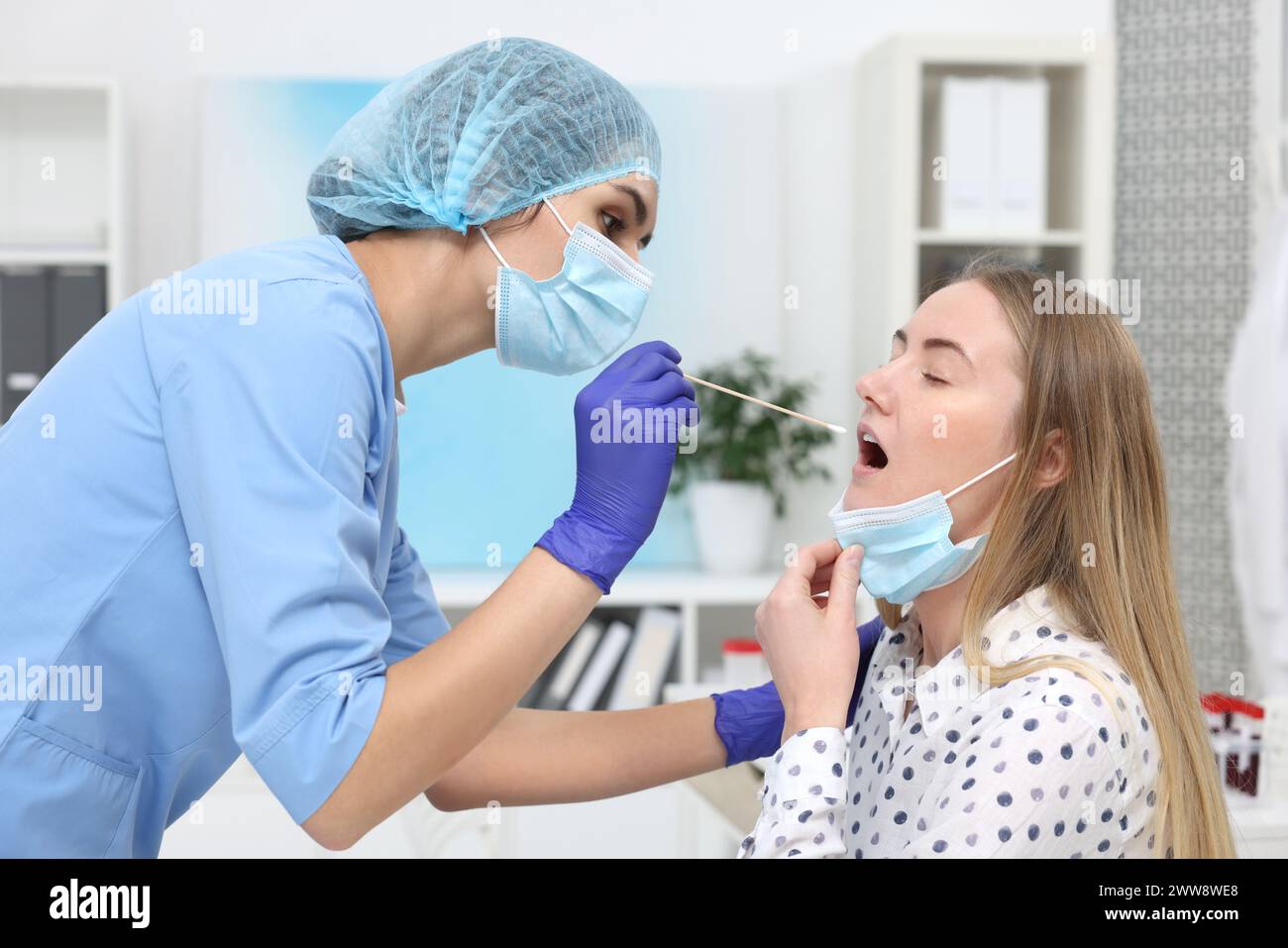 Laboratory testing. Doctor taking sample from patient's mouth with ...
